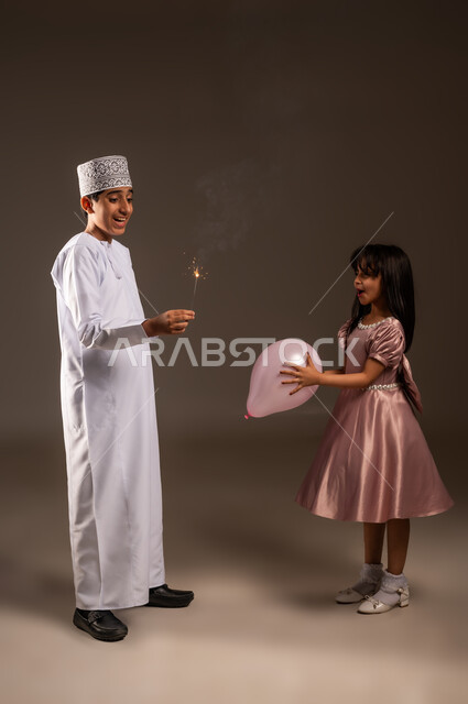 Boy holding magic fireworks wand, Omani Gulf Arab boy and girl wearing ...