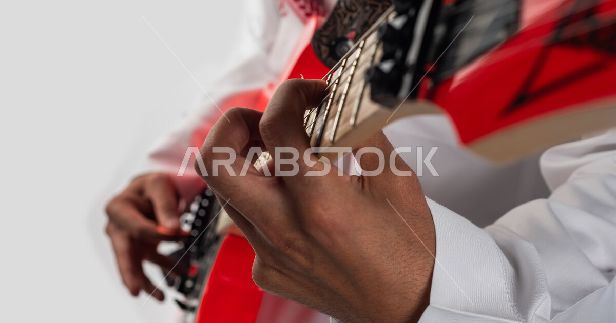 A close-up of a Saudi Arabian Gulf man playing the electronic guitar ...