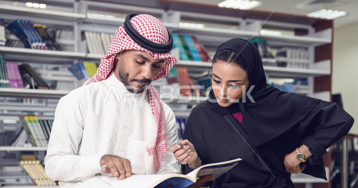 Two Saudi Arabian Gulf students in the university library, reading a ...