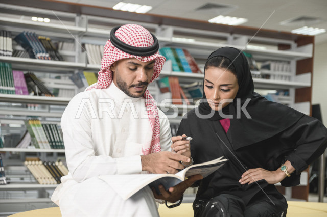 Two Saudi Arabian Gulf students in the university library, reading a ...