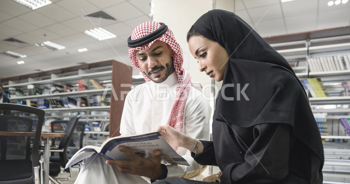 Two Saudi Arabian Gulf students in the university library, reading a ...