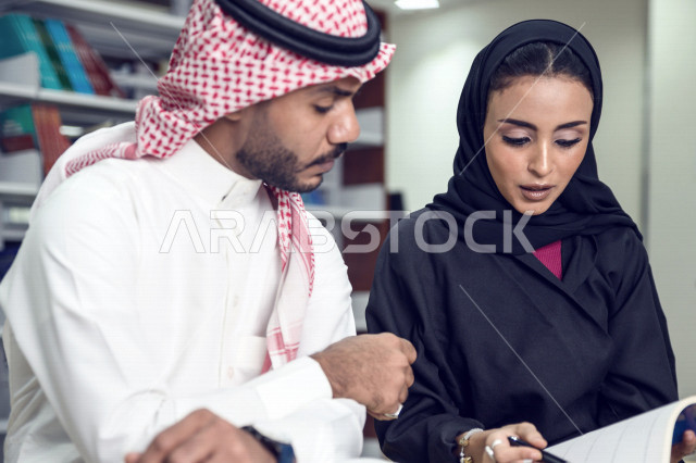 Two Saudi Arabian Gulf students in the university library, reading a ...