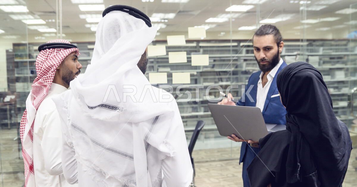 A Saudi Gulf Arab work team at the workplace, taking notes and tasks on ...