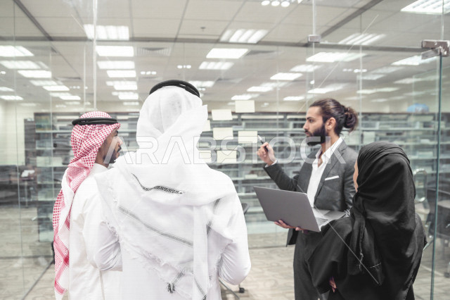 A Saudi Gulf Arab work team at the workplace, taking notes and tasks on ...