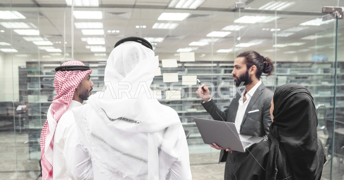 A Saudi Gulf Arab work team at the workplace, taking notes and tasks on ...