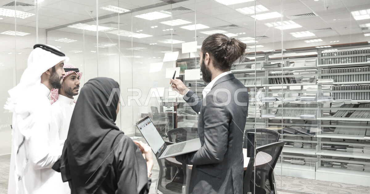 A Saudi Gulf Arab work team at the workplace, taking notes and tasks on ...
