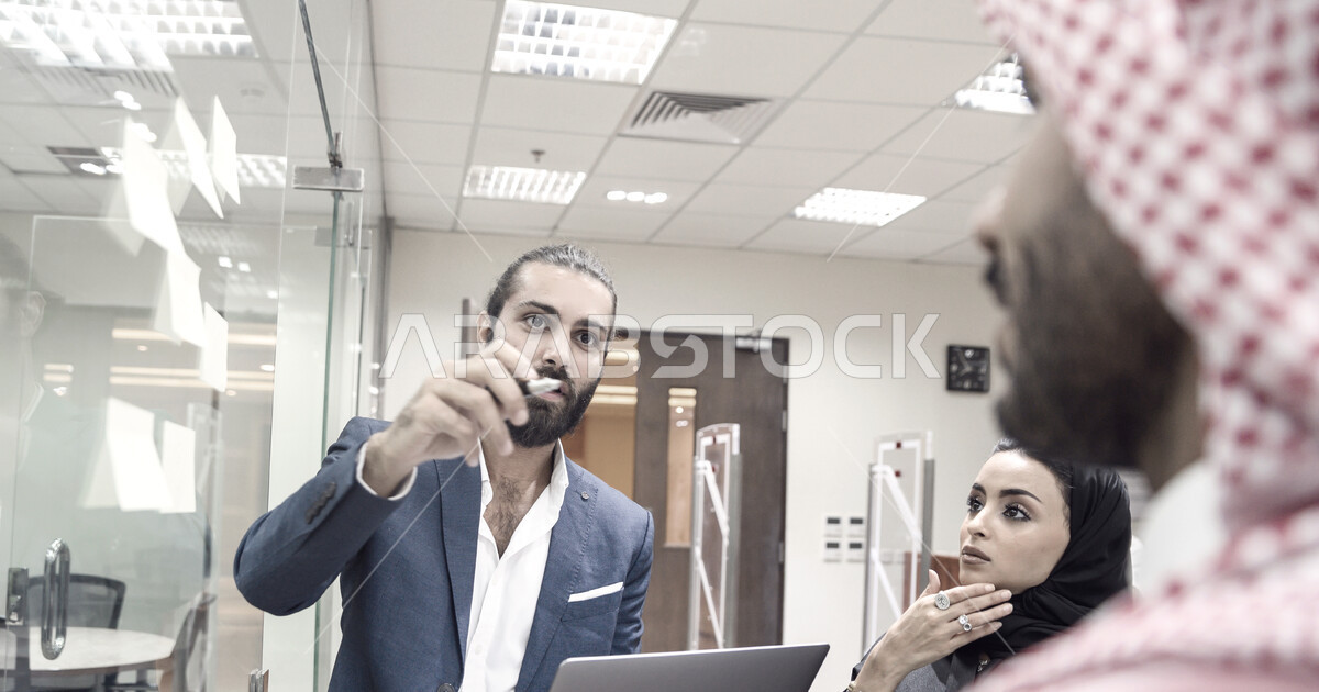 A Saudi Gulf Arab work team at the workplace, taking notes and tasks on ...