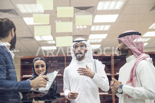 A Saudi Gulf Arab work team at the workplace, taking notes and tasks on ...