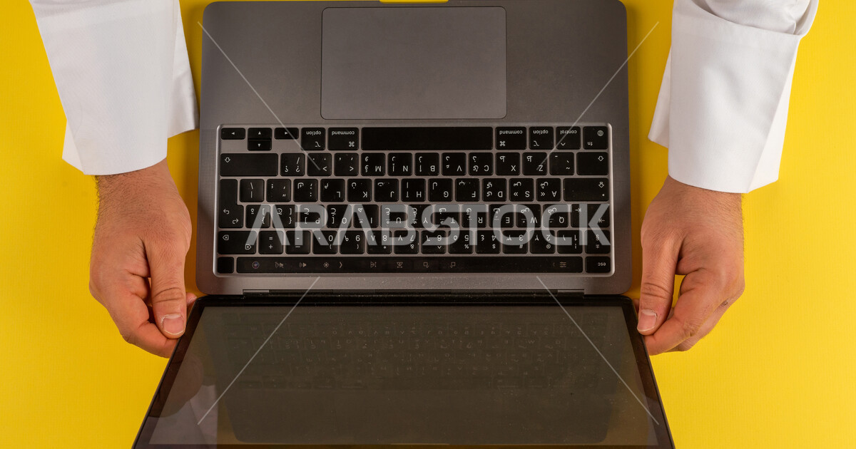 A close-up of the hand of a Saudi Arabian Gulf man using a laptop ...
