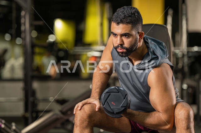 Using weights, bodybuilding, young Arab Gulf Emirati man wearing ...