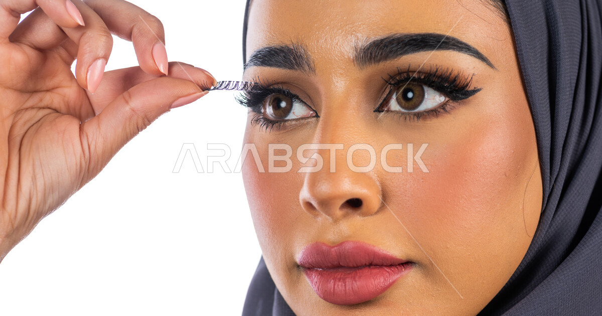 Portrait of a Saudi Arabian Gulf woman applying false eyelashes to get ...