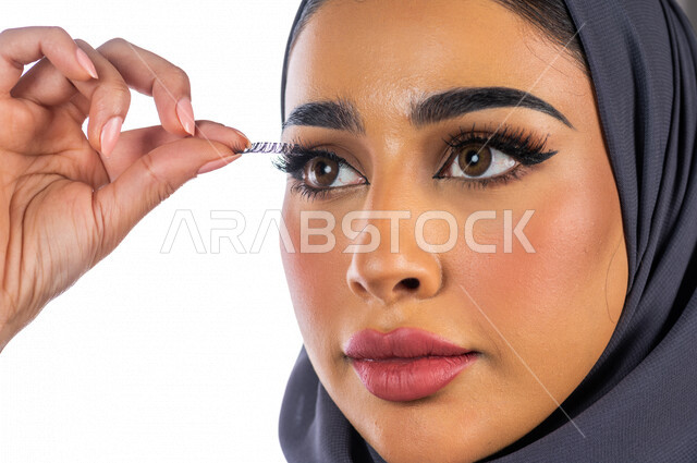 Portrait of a Saudi Arabian Gulf woman applying false eyelashes to get ...
