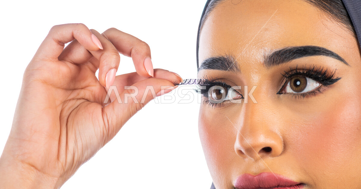 Portrait of a Saudi Arabian Gulf woman applying false eyelashes to get ...
