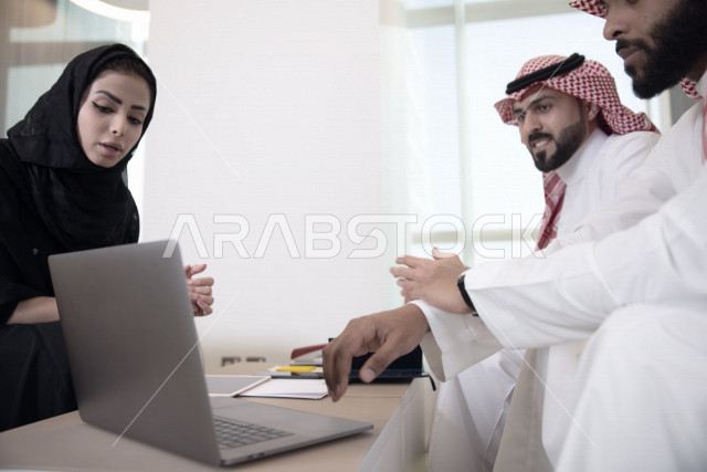 A Saudi Arabian Gulf work team, a businessman using a laptop computer ...