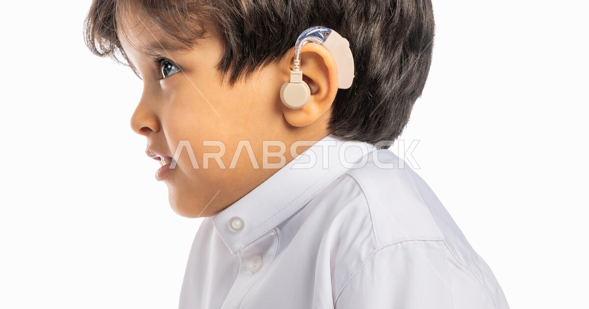 Portrait of a young Saudi Arabian deaf child wearing a hearing aid ...