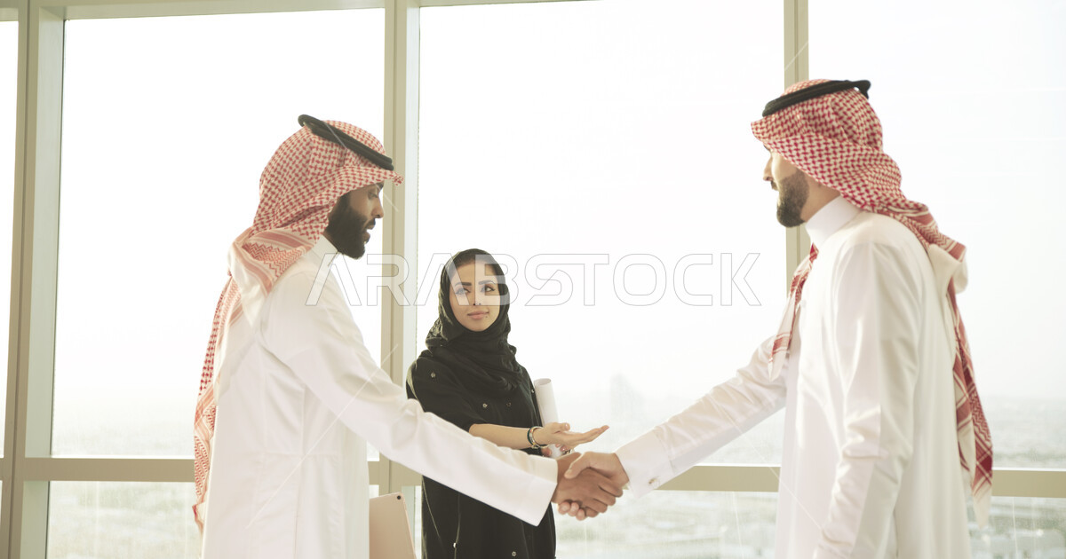 Two Saudi Arabian men shake hands after a successful business meeting ...
