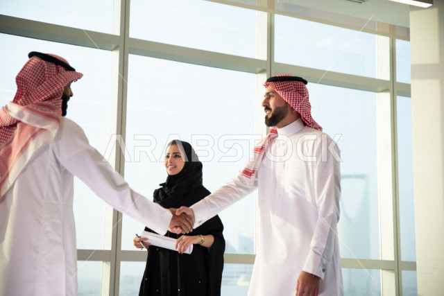 Two Saudi Arabian men shake hands after a successful business meeting ...