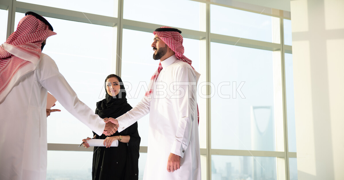 Two Saudi Arabian men shake hands after a successful business meeting ...