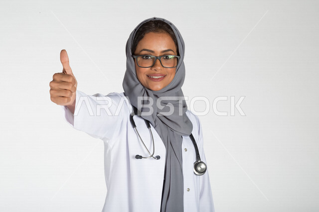 Portrait of a Saudi Arabian Gulf doctor wearing glasses and raising her ...