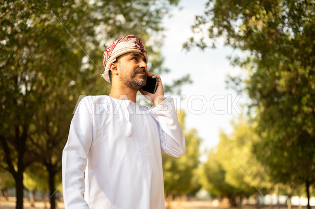 Making a phone call, having fun in green parks, outdoor walk, an Arab ...