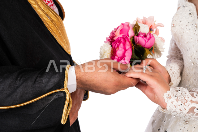 A close-up portrait of a groom in the official Saudi attire holding the ...