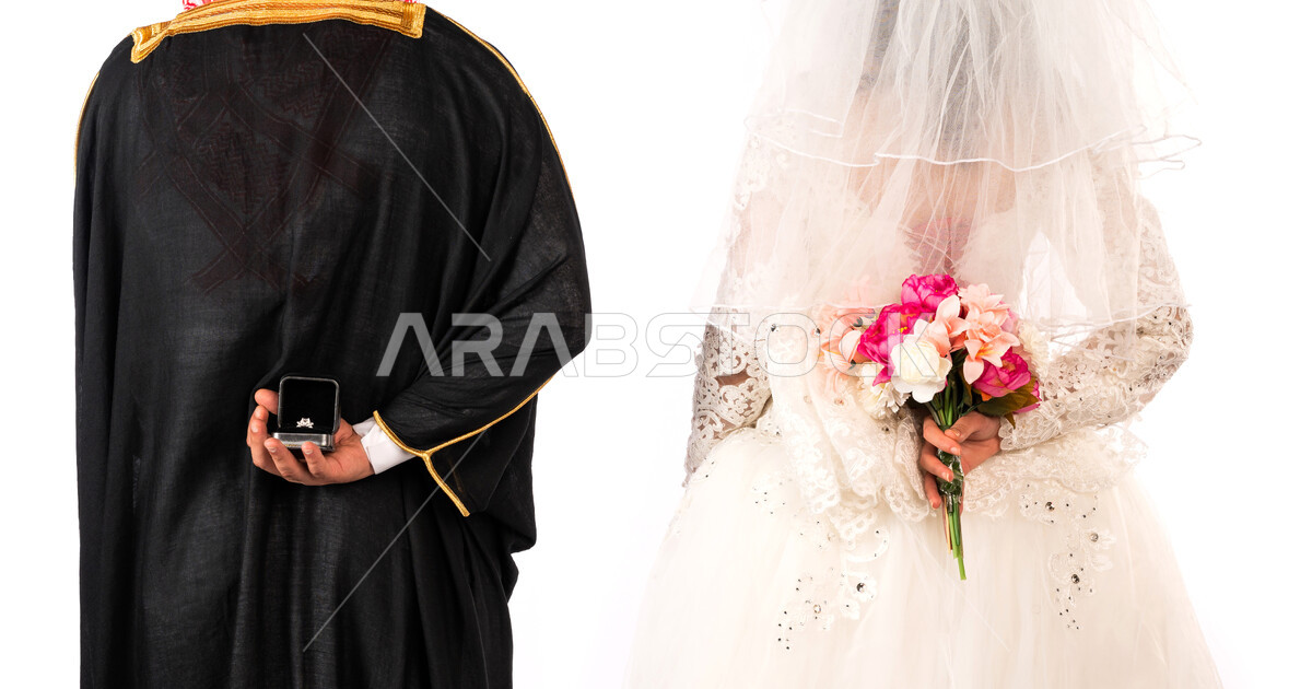 Angled portrait of a groom in official Saudi dress holding a wedding ...