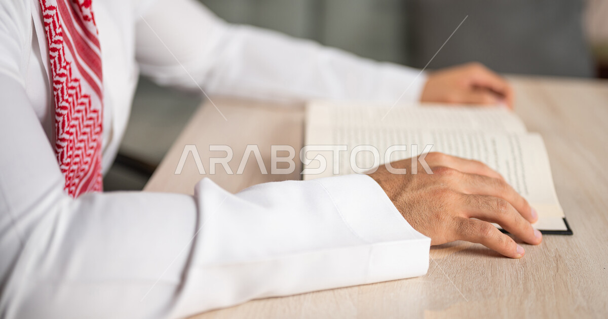 A close-up of a Saudi Arabian Gulf man reading a book, a scientific ...