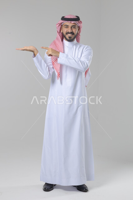Pointing to palm, standing up straight, portrait of a Saudi Arabian ...