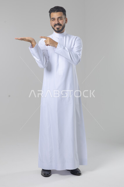 Pointing to palm, standing up straight, portrait of a Saudi Arabian ...