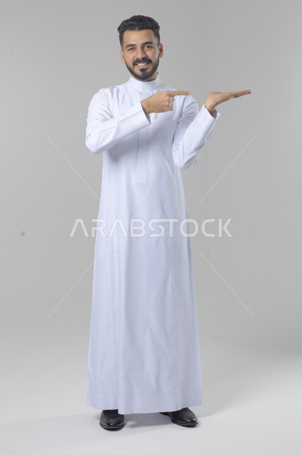 Pointing to palm, standing up straight, portrait of a Saudi Arabian ...