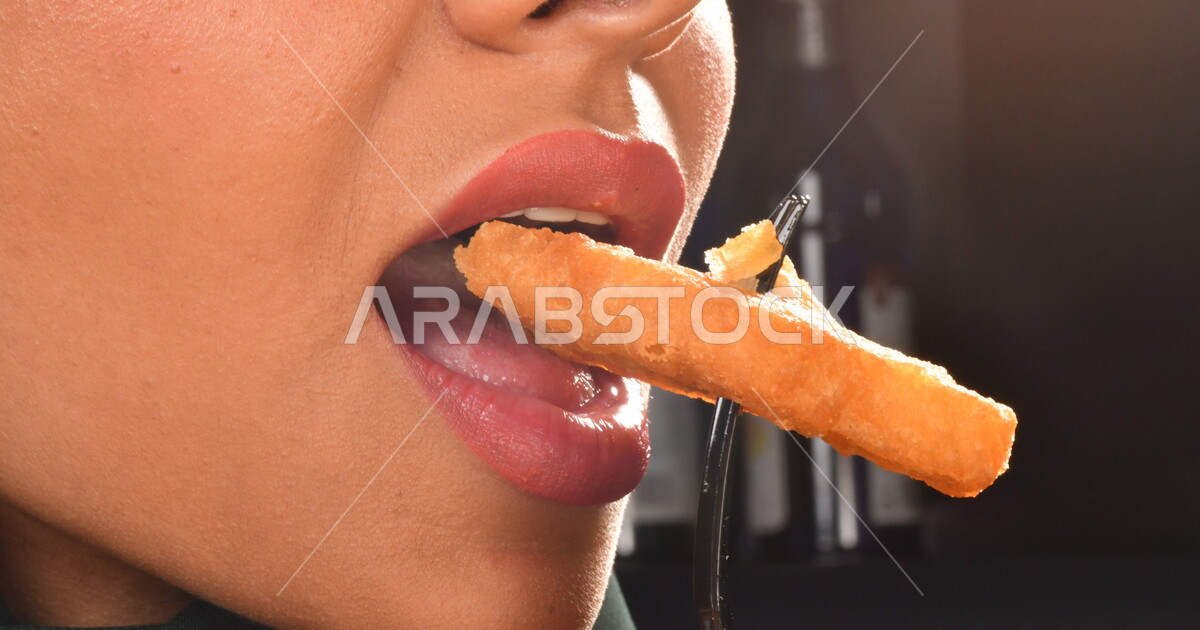 A Saudi Arabian Gulf woman eating fried potatoes, enjoying eating ...