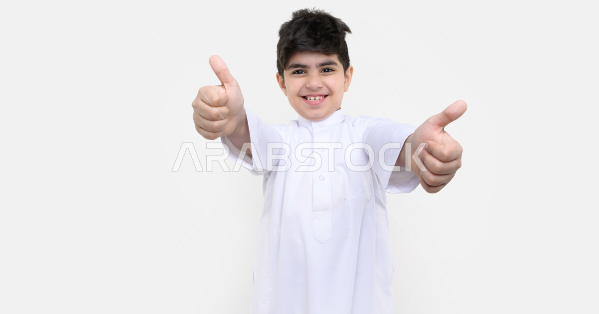 Portrait of a happy Saudi Arabian Gulf Arab boy raising his hand up and ...