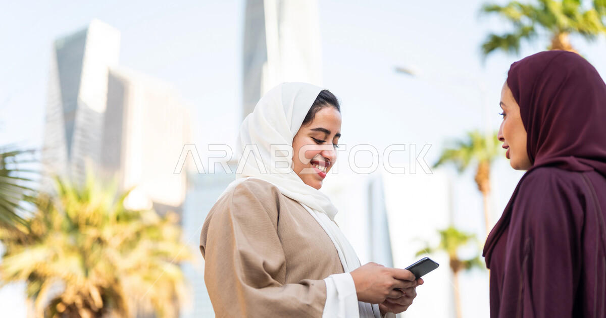 A Saudi Arabian Gulf woman talking with a Saudi woman using a mobile ...