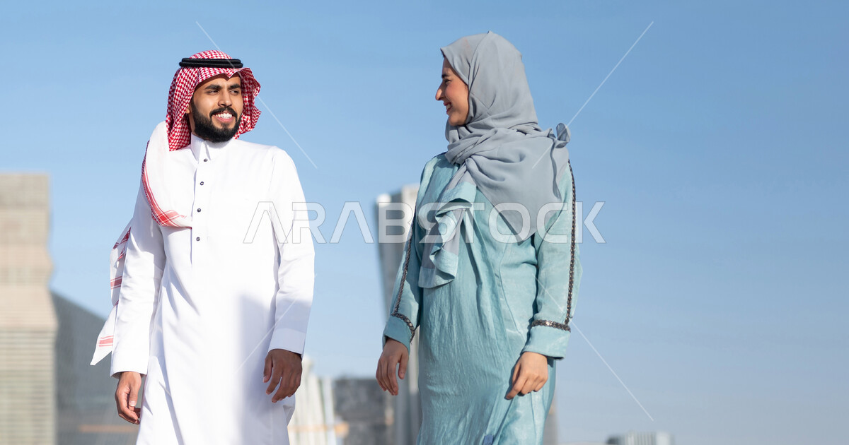 A happy Saudi Arabian Gulf couple walking in a park in Riyadh, outdoor ...