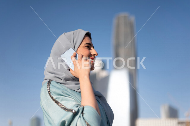 A smiling Saudi Arabian Gulf woman with her mobile phone making a phone ...