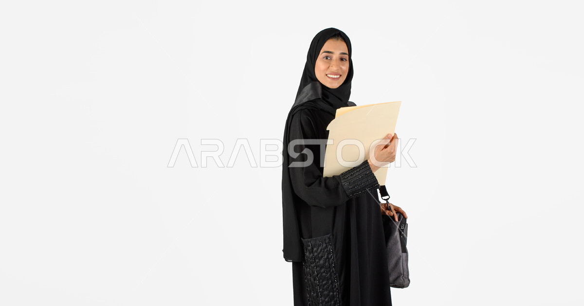 Portrait of a veiled Saudi Arab university student holding a university ...