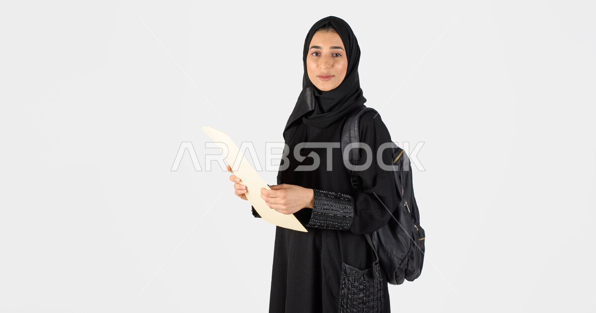 Portrait of a veiled Saudi Arab university student holding a university ...