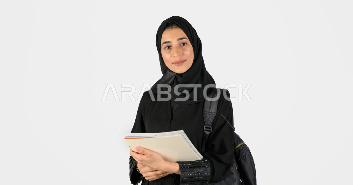 Portrait of a veiled Saudi Arab university student holding a university ...