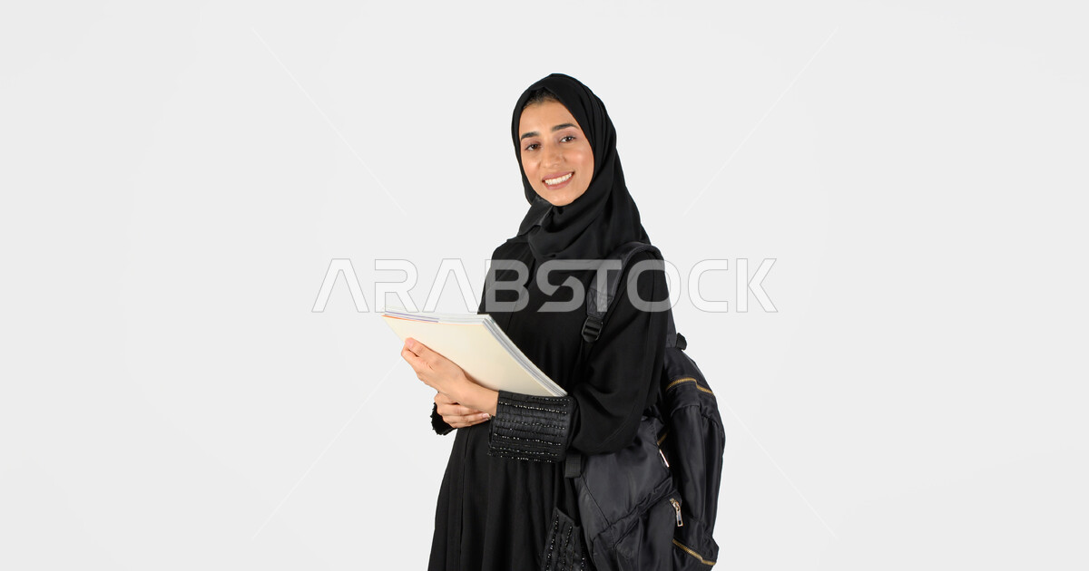 Portrait of a veiled Saudi Arab university student holding a university ...