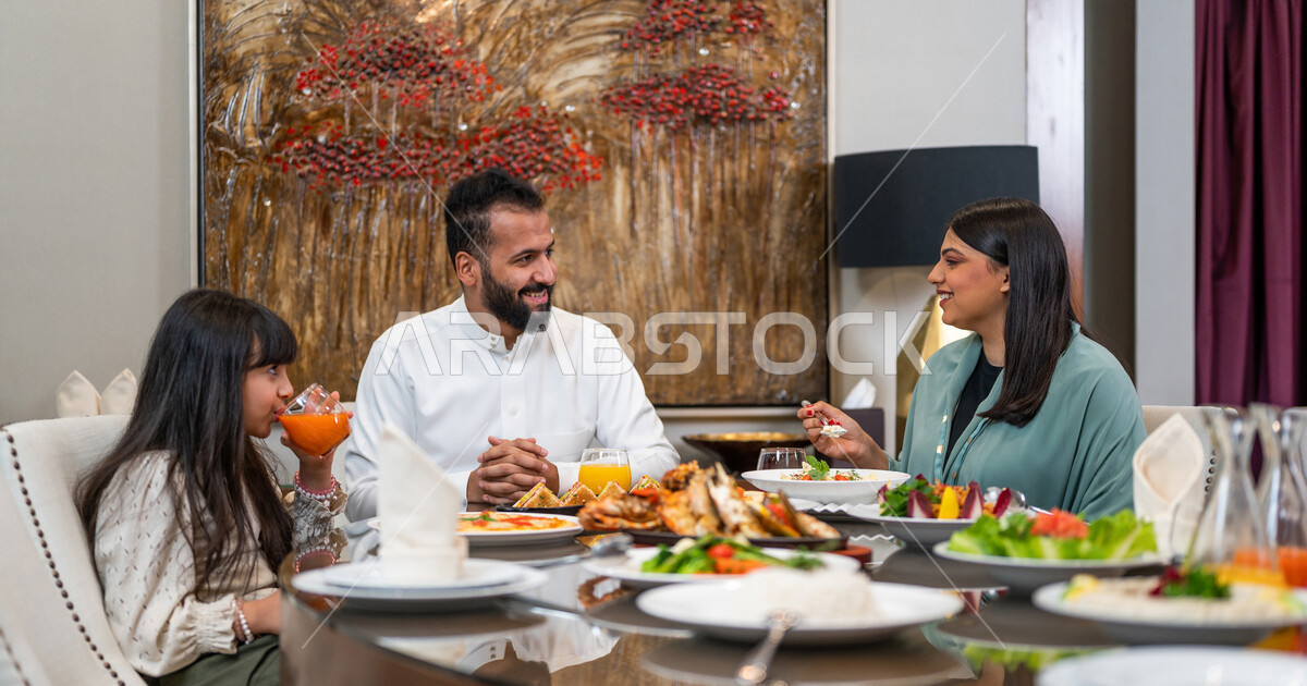 A Saudi Arabian Gulf family sitting in the restaurant, a dining table ...