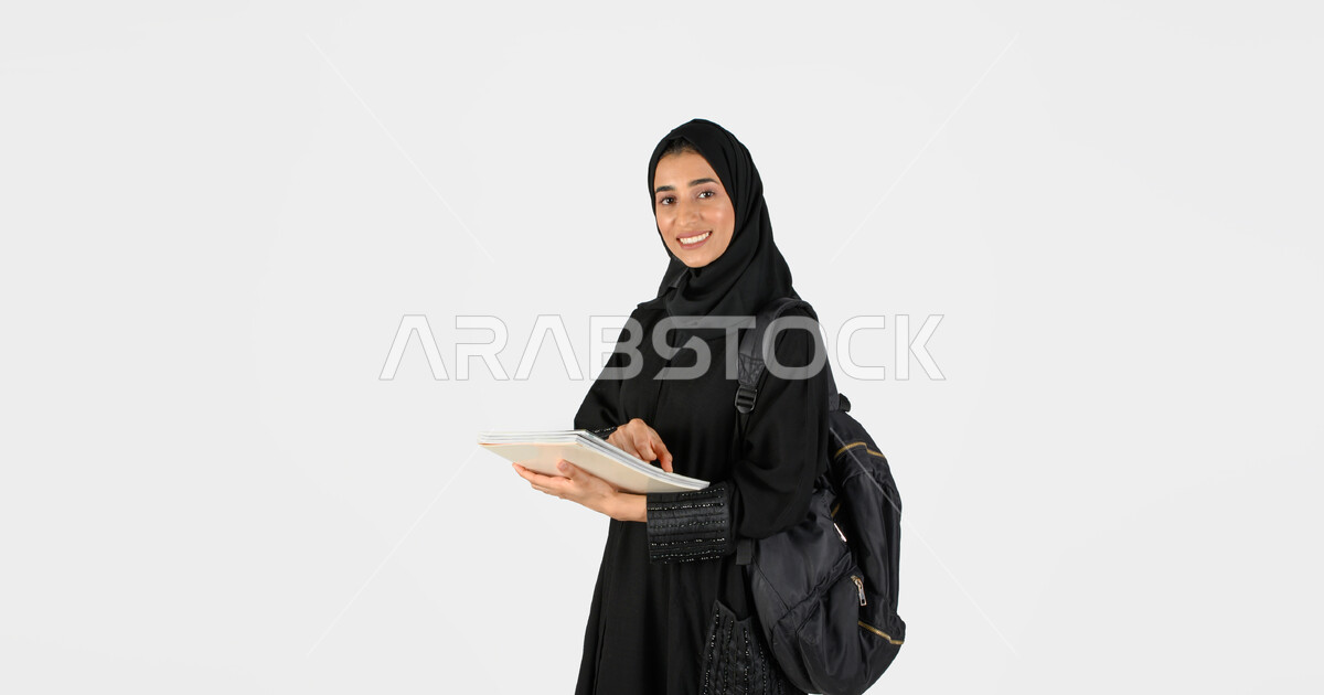 Portrait of a veiled Saudi Arab university student holding a university ...