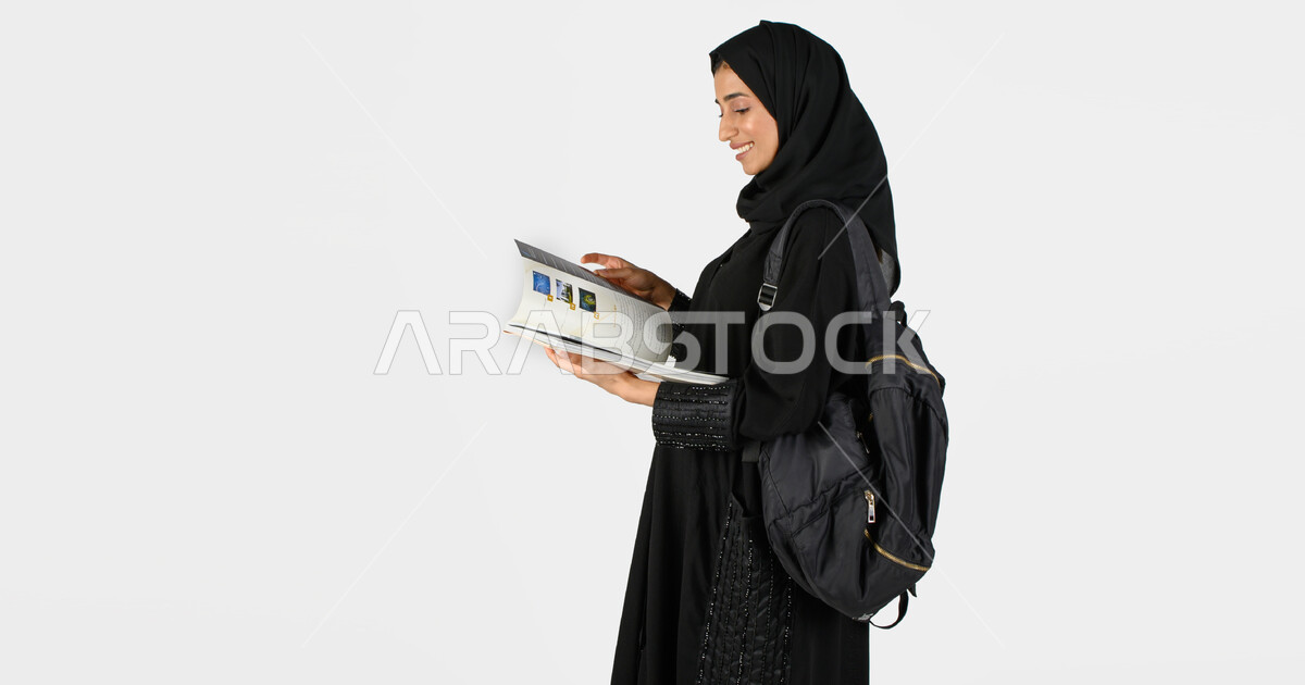 Portrait of a veiled Saudi Arab university student holding a university ...