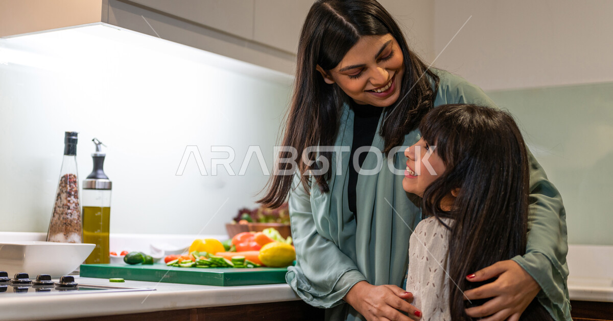 ام عربية خليجية سعودية تقوم باحتضان ابنتها في المطبخ، تعليم الابنة ...