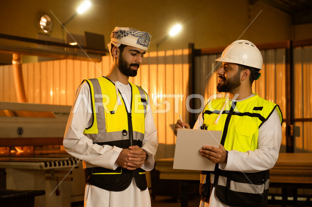 Talking about work matters, two Arab Gulf engineers from Oman wearing ...