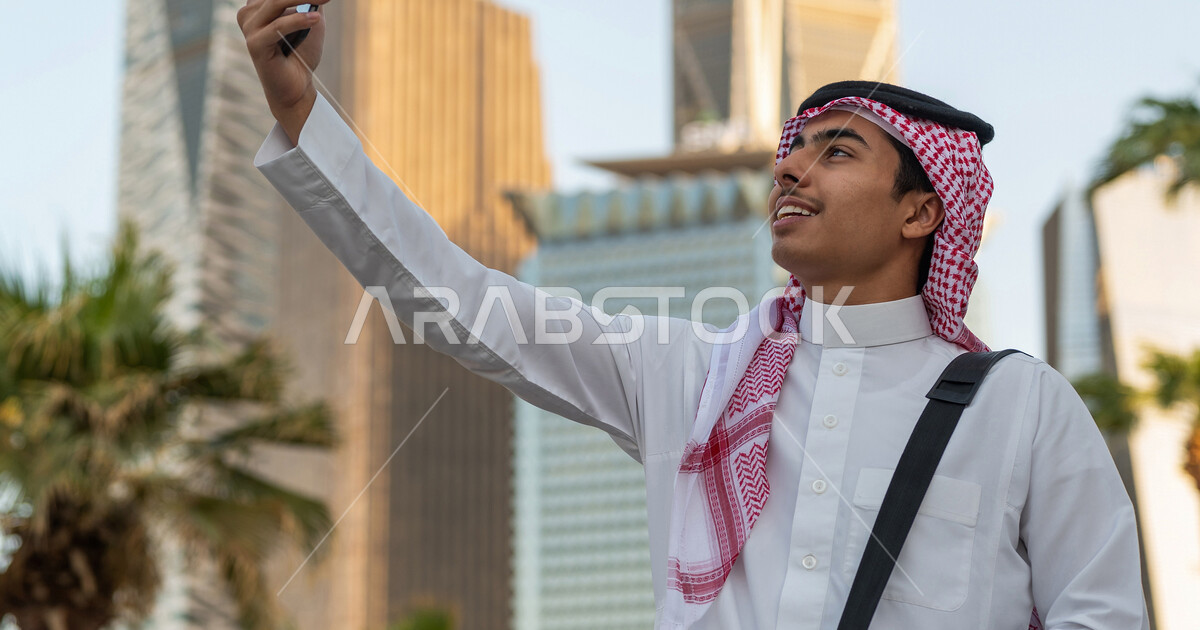 A smiling Saudi Arabian Gulf young man, wearing a traditional dress and ...