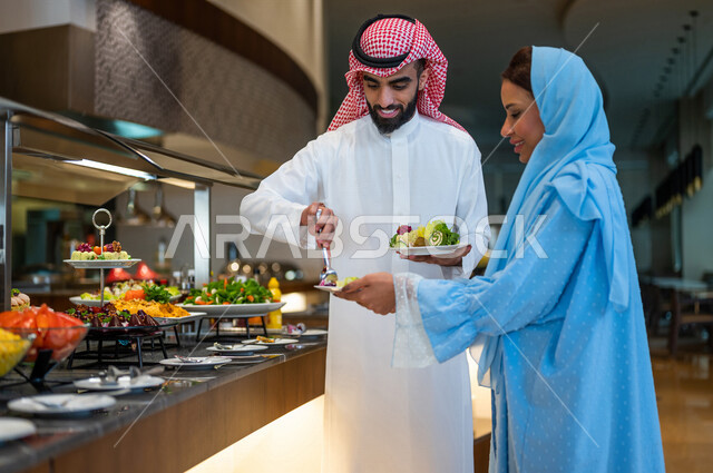 A Saudi Arabian couple scooping food from the buffet in the restaurant ...