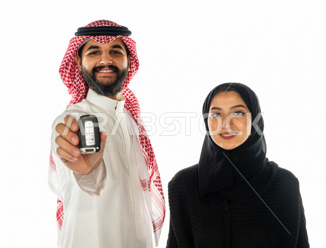 A close-up of a Saudi Arabian Gulf man accompanied by his wife, holding ...
