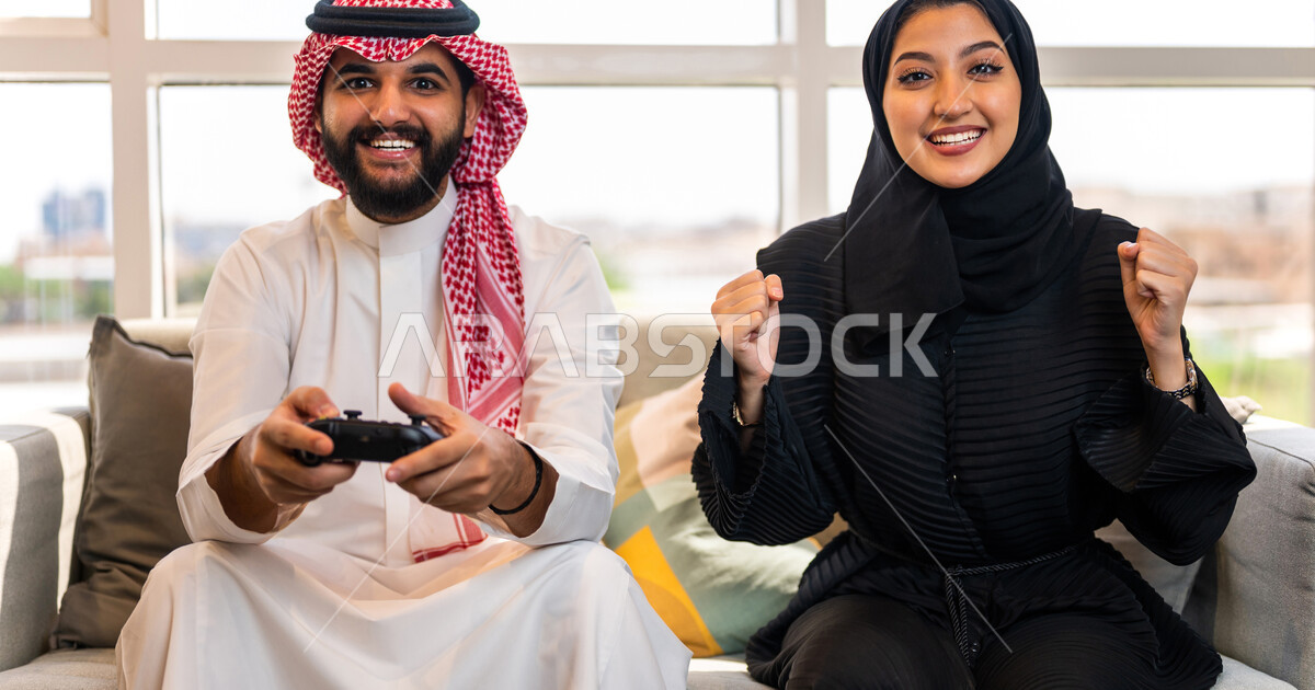زوجان عربيان خليجيان سعوديان يجلسان في غرفة المعيشة ، قضاء وقت ممتع