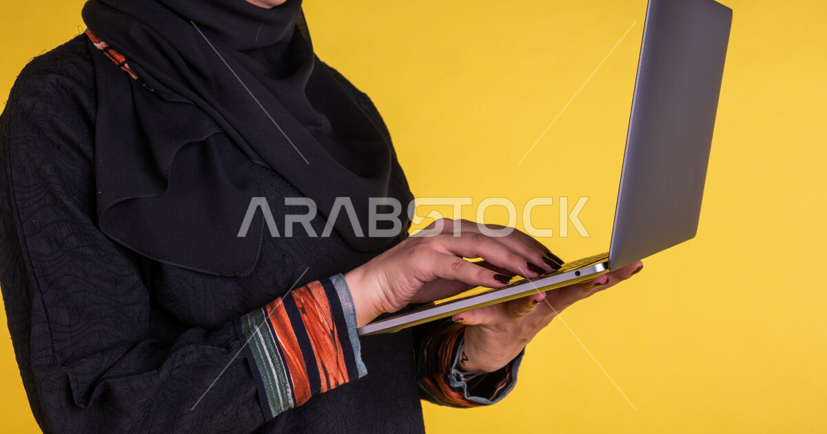 Portrait of a Saudi Arabian Gulf woman using her laptop computer to get ...