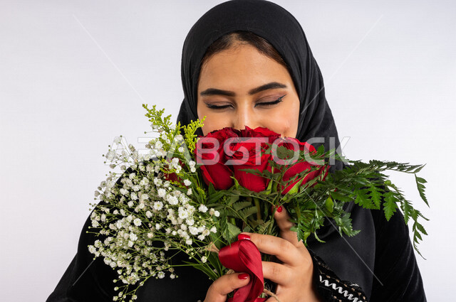 Portrait of a Saudi Arabian Gulf woman holding a beautiful red rose ...